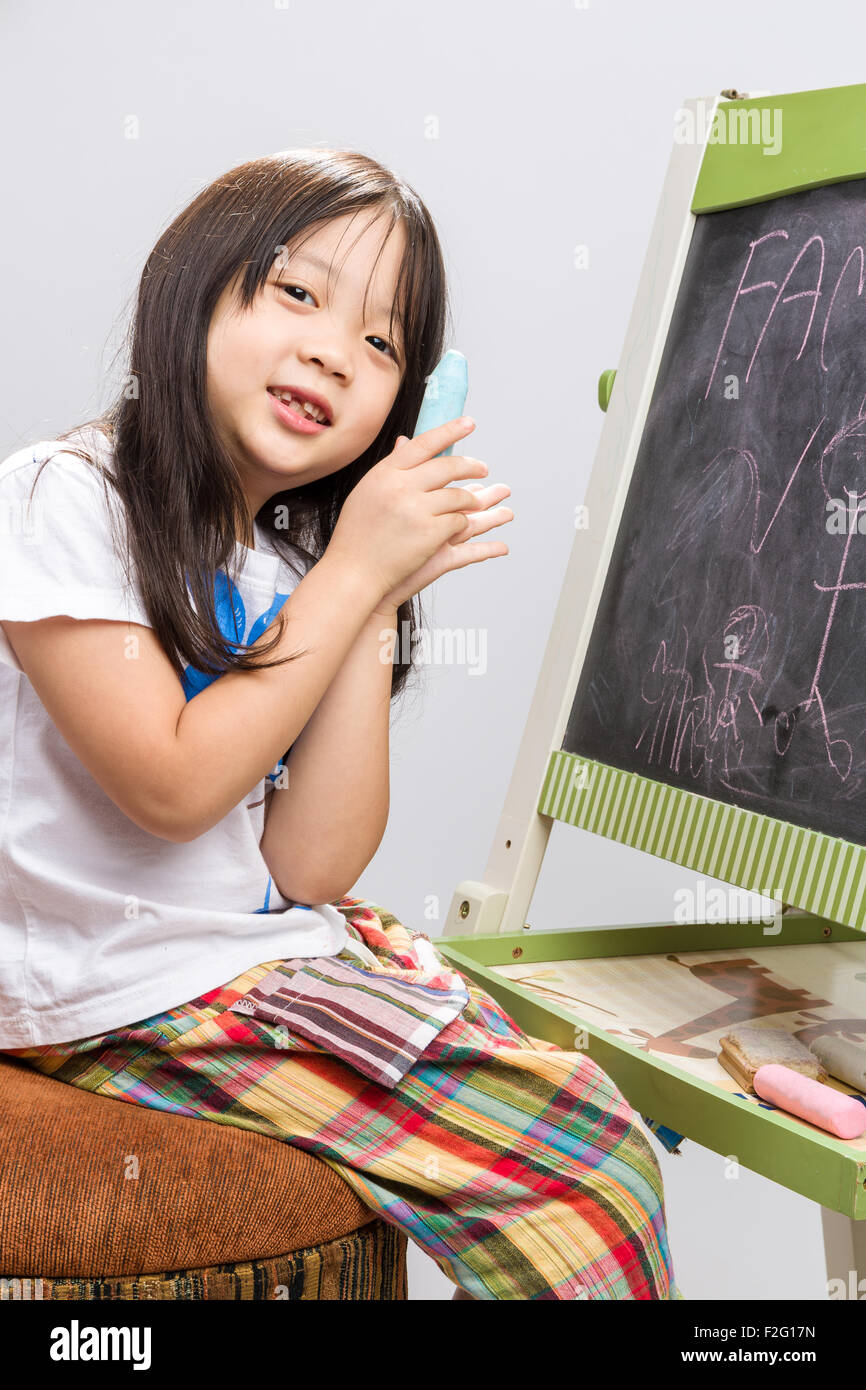 Little kid sit beside a blackboard studio isolated Stock Photo - Alamy