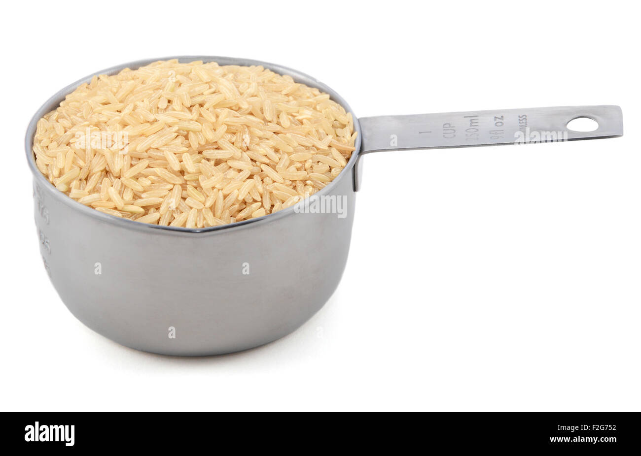 Long grain brown rice in an American measuring cup, isolated on a white ...
