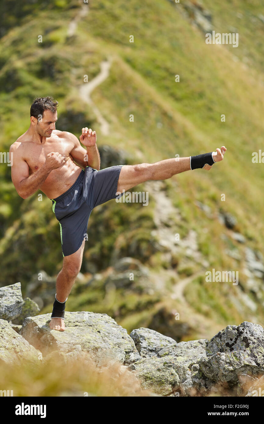 Kickboxer or muay thai fighter practicing shadow boxing on a mountain ...