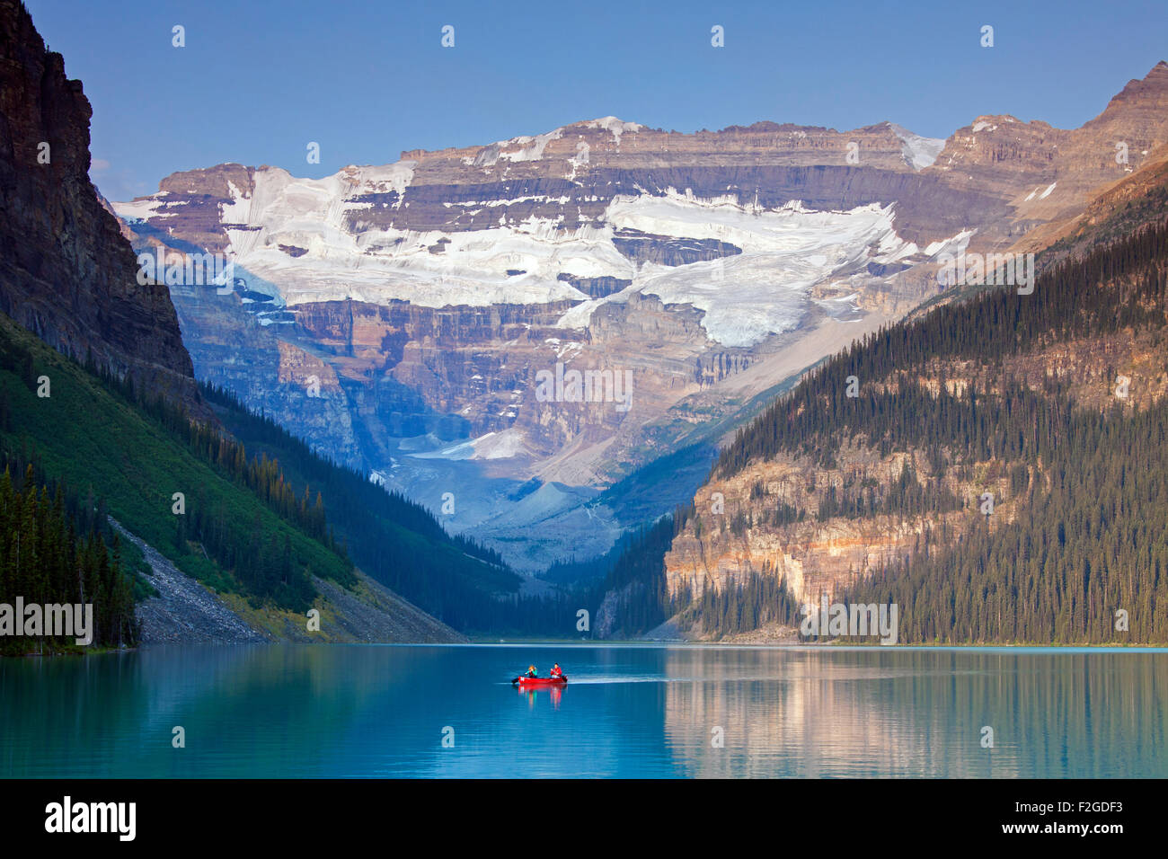 Tourists in red canoe on glacial Lake Louise with Victoria glacier ...