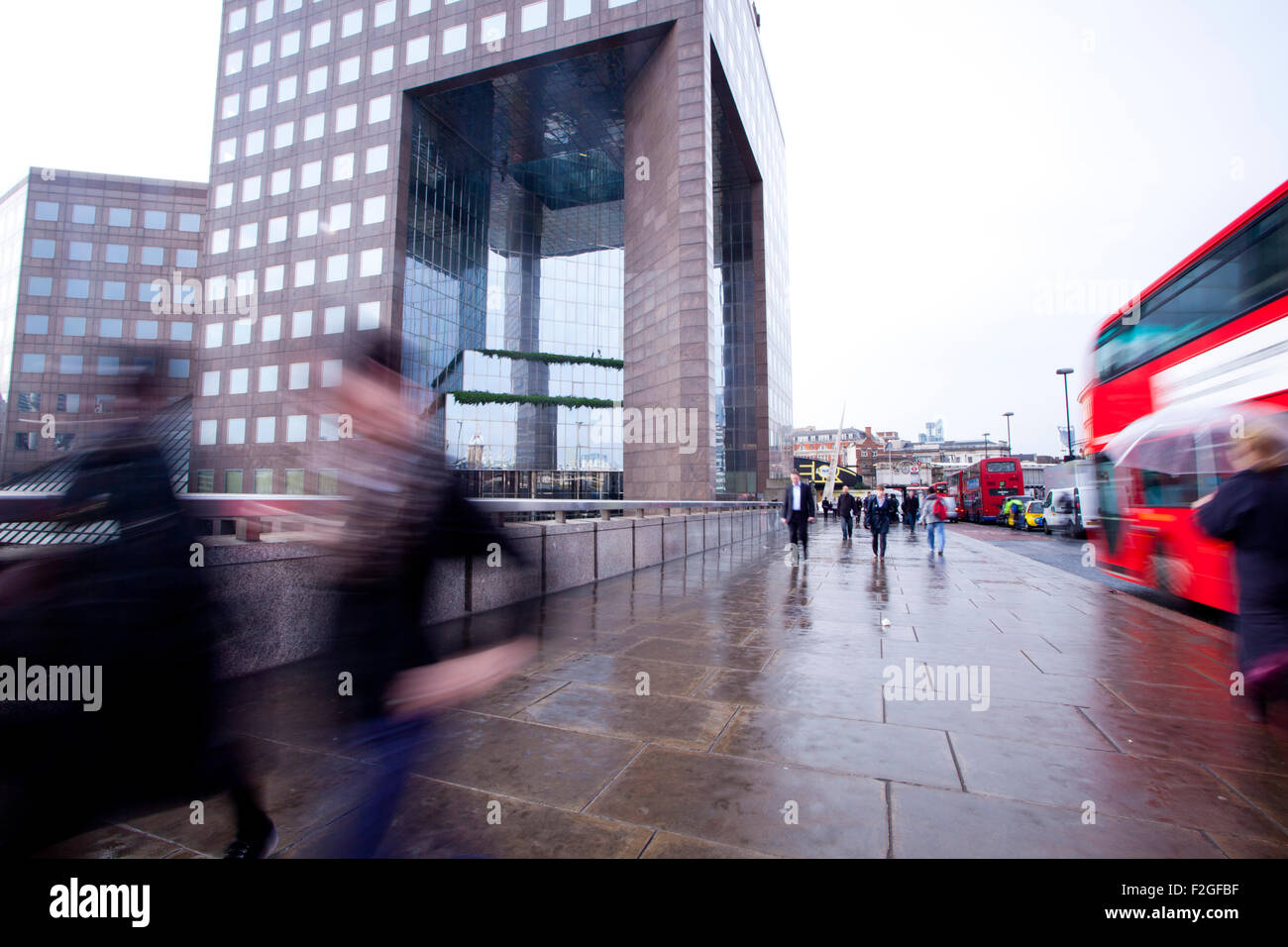 A view of people walking past a red bus and number 1 London Bridge ...
