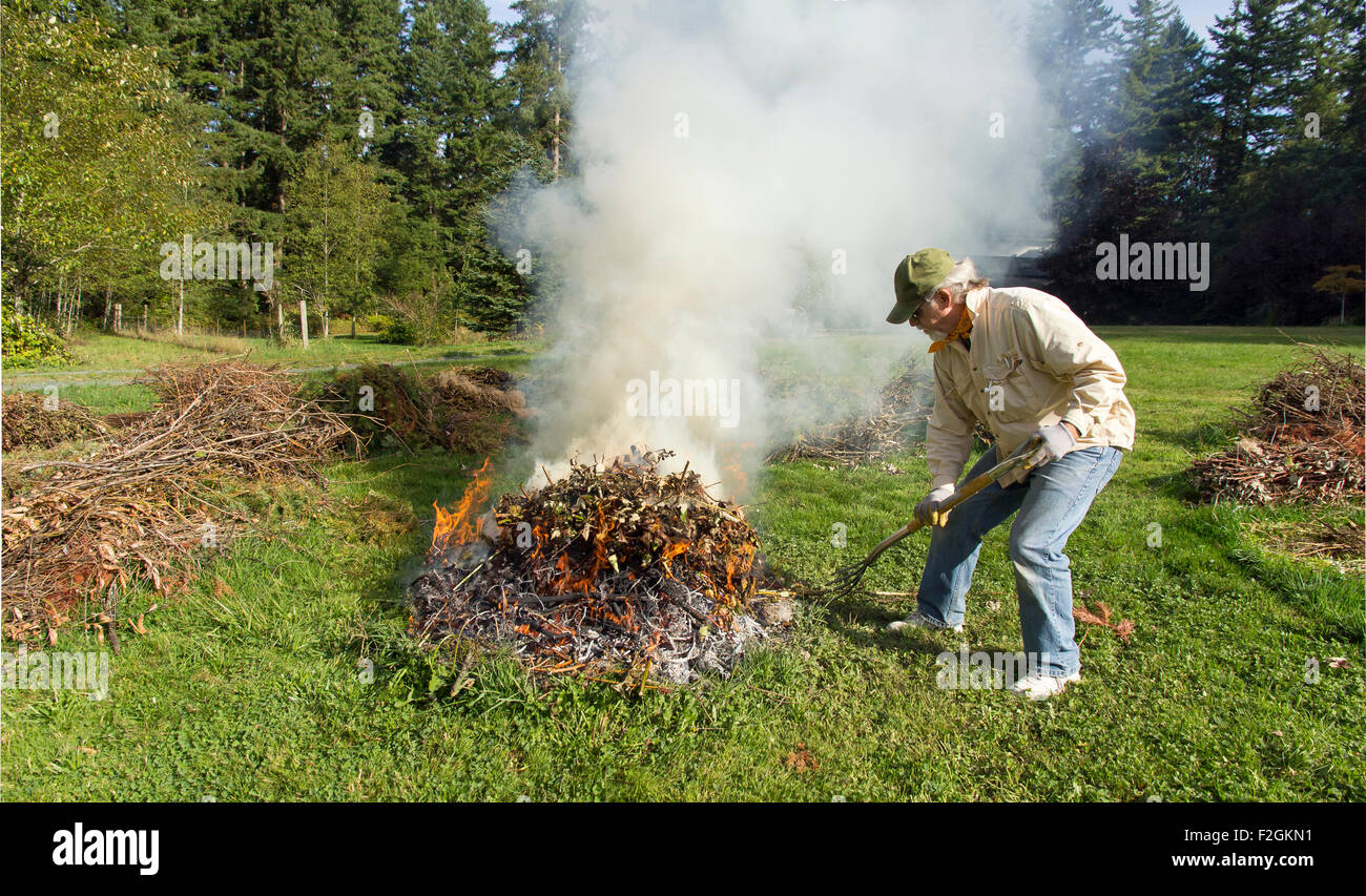 Man feeds an outdoor garden burn pile Stock Photo - Alamy