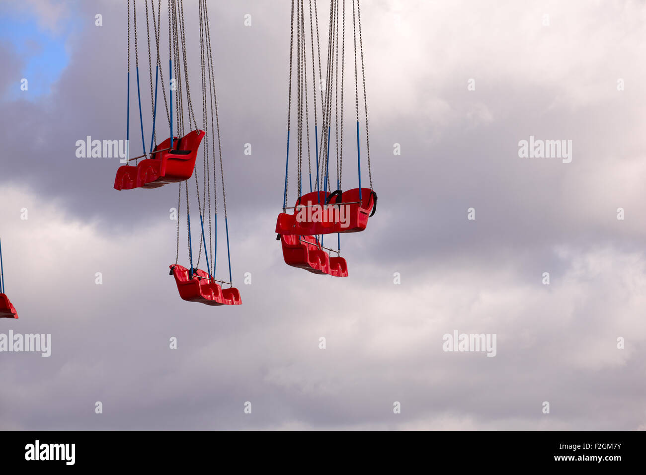 Red Carousel seats on cloudy sky Stock Photo - Alamy