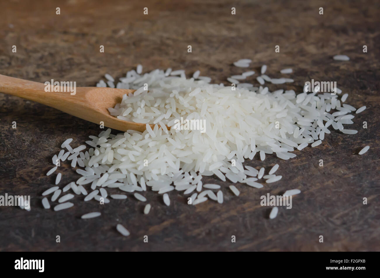 white rice grains with wooden spoon on wooden table Stock Photo - Alamy