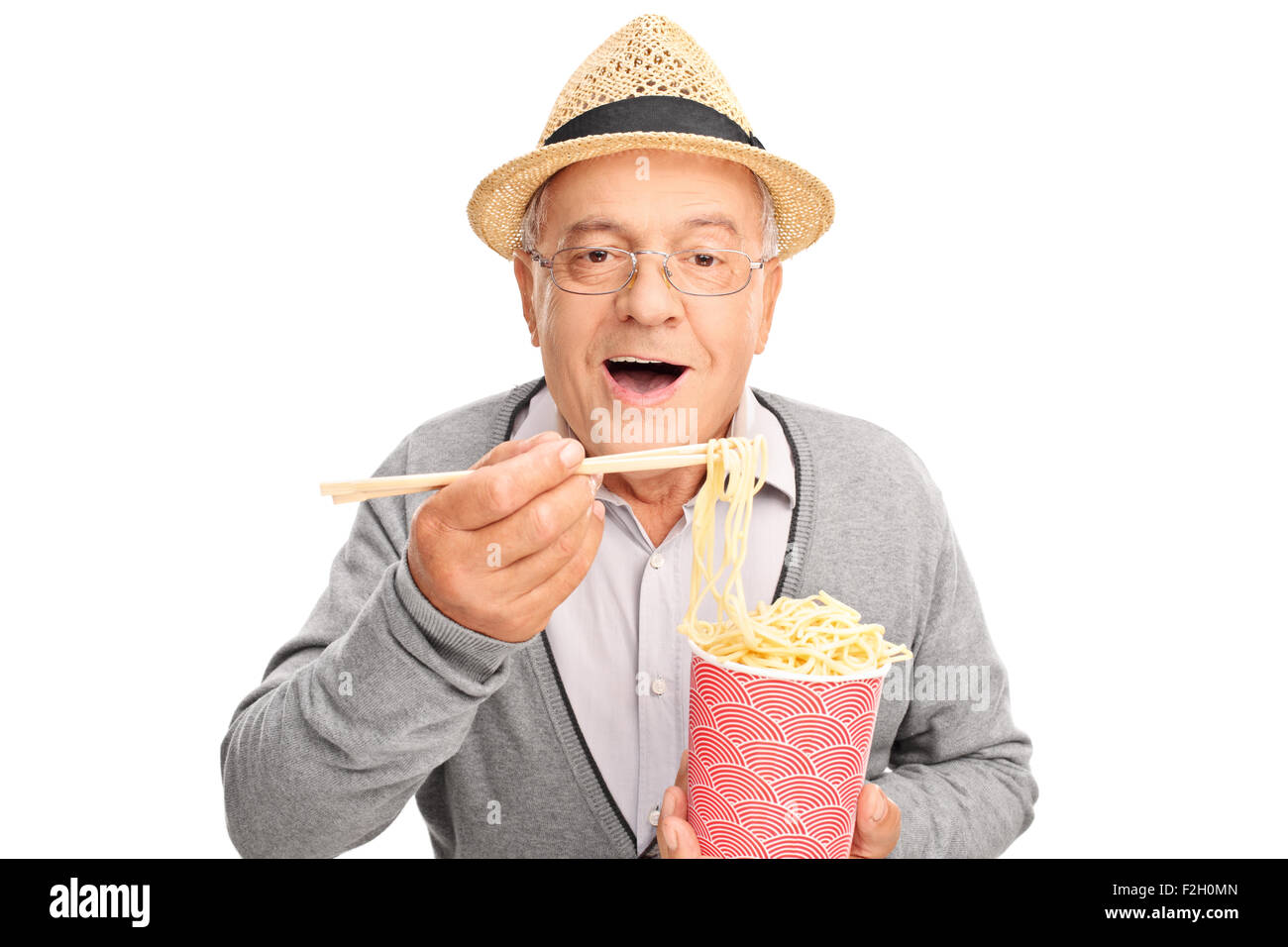 Senior gentleman eating Chinese food with sticks and looking at the ...