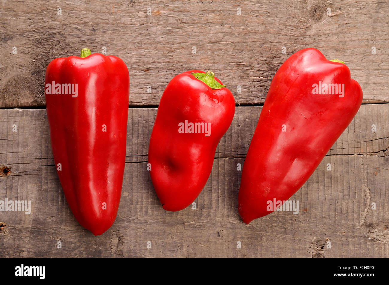 Three red fresh paprika on an old used barn wood Stock Photo - Alamy