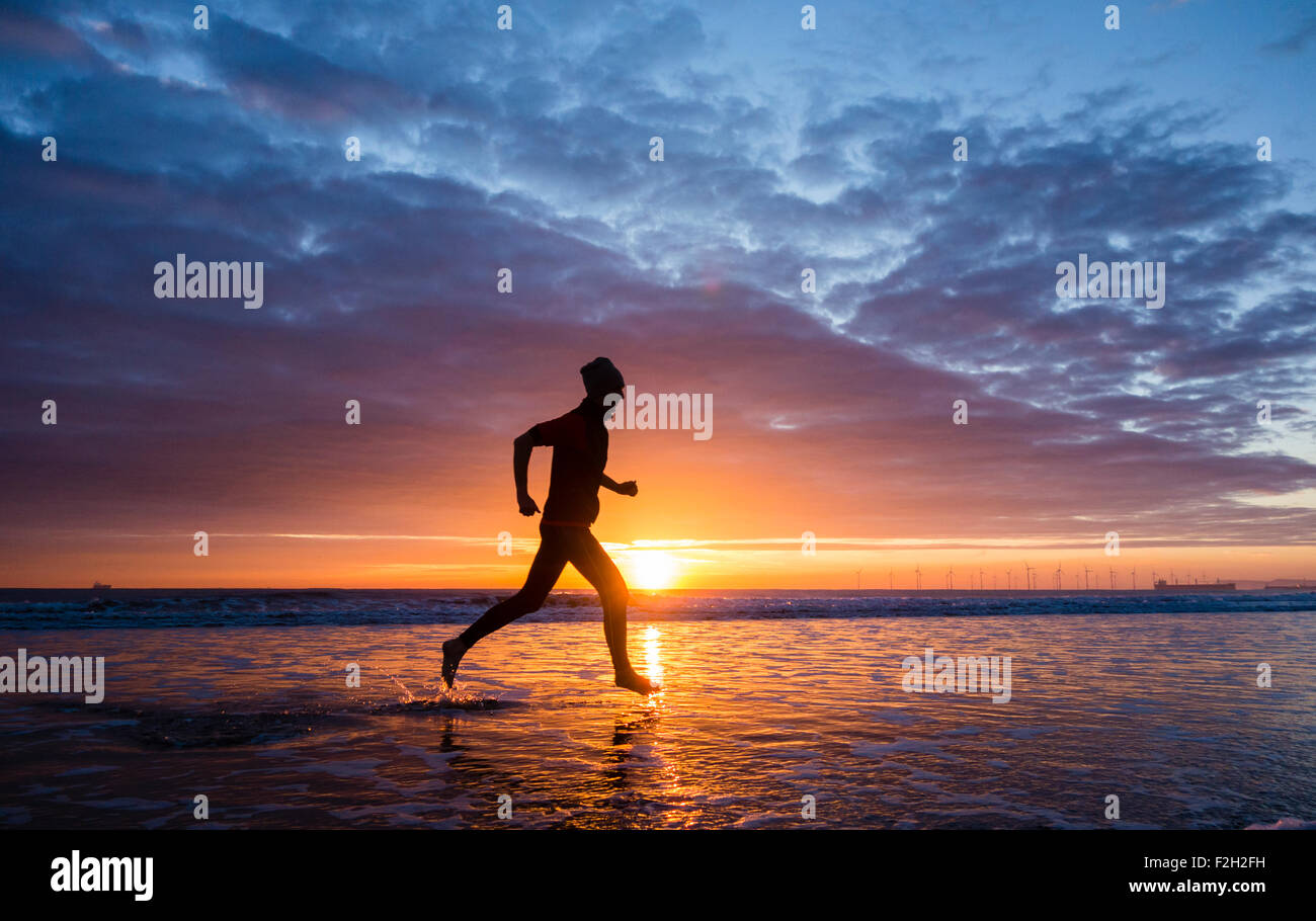 Man running barefoot on beach at sunrise. UK Stock Photo - Alamy