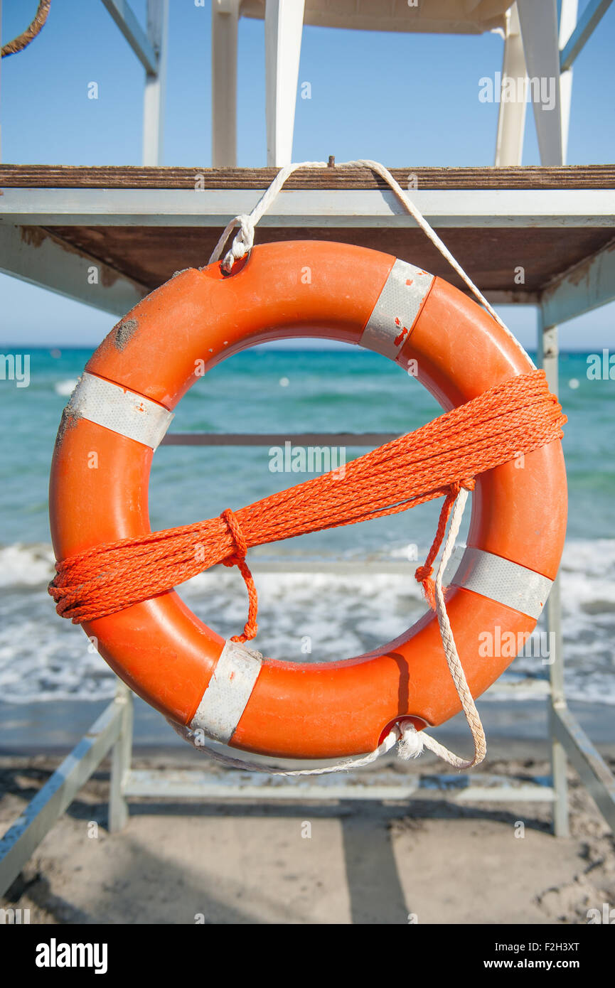 Orange life preserver on a beach with out of focus sea in background ...
