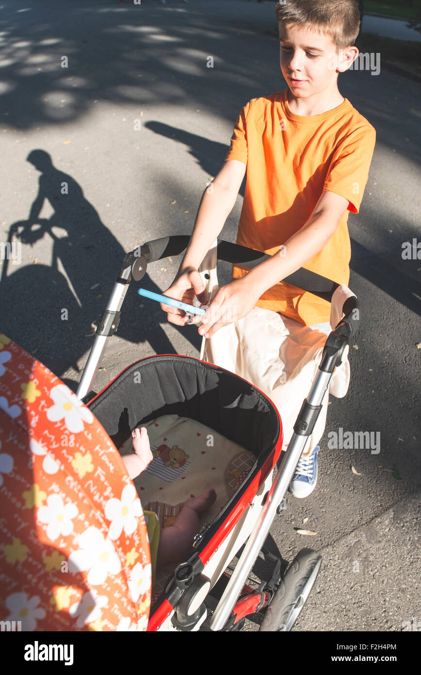 Child with smartphone taking a picture of baby in buggy Stock Photo - Alamy