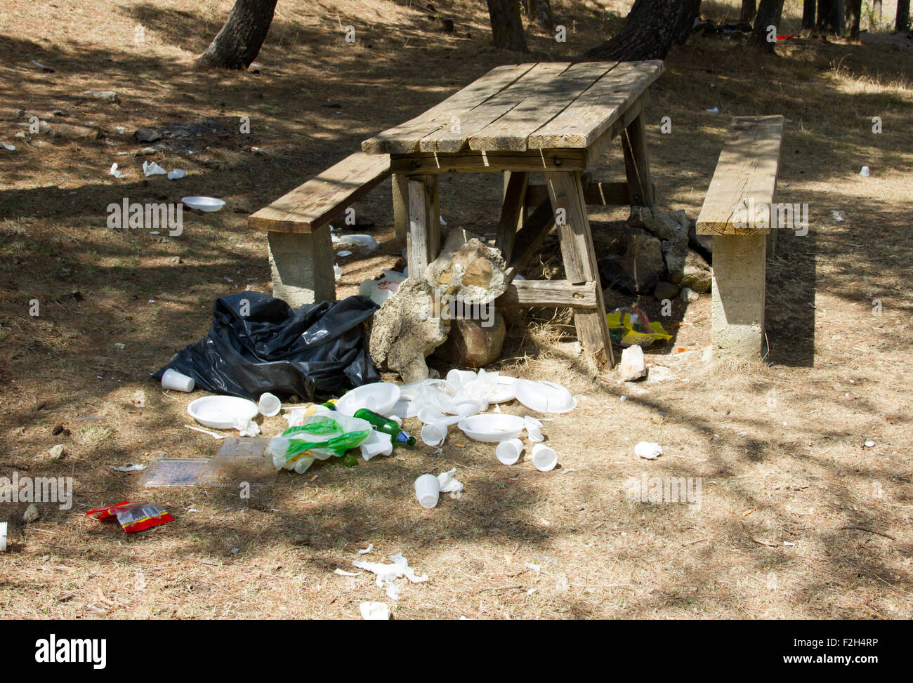 Wooden picnic table with garbage strewn near Stock Photo - Alamy