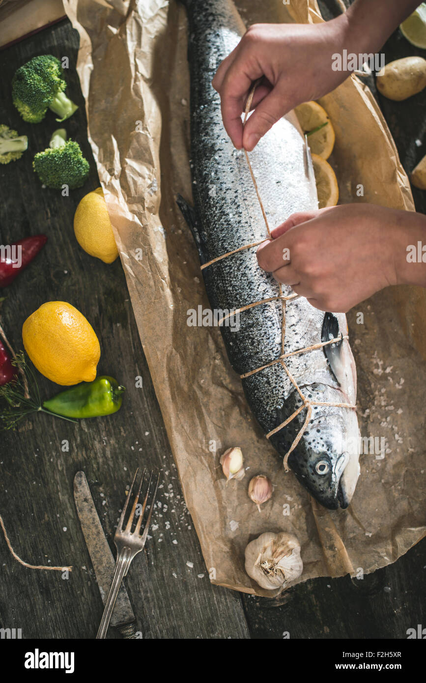 Tying a rope on fish for grilling. Baking paper Stock Photo - Alamy