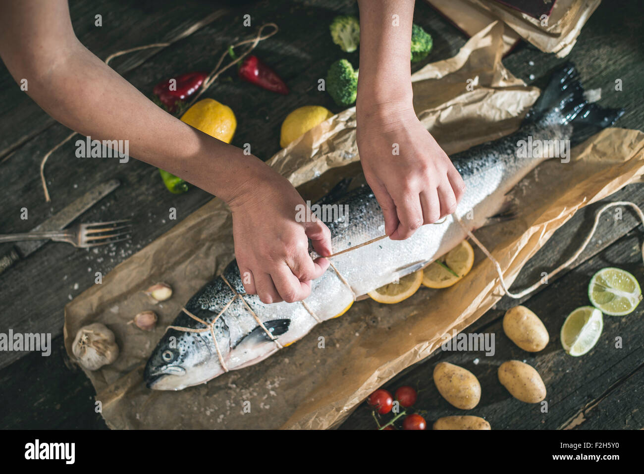 Tying a rope on fish for grilling. Baking paper Stock Photo - Alamy