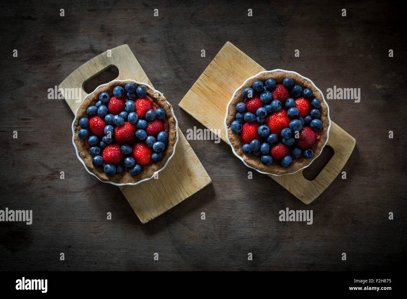 Berry tartetelets in baking dishes on wooden plates. Top view Stock ...