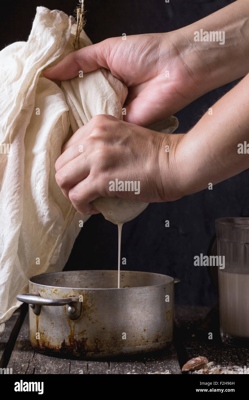Process of making non-dairy almond milk - woman's hands extracting milk ...