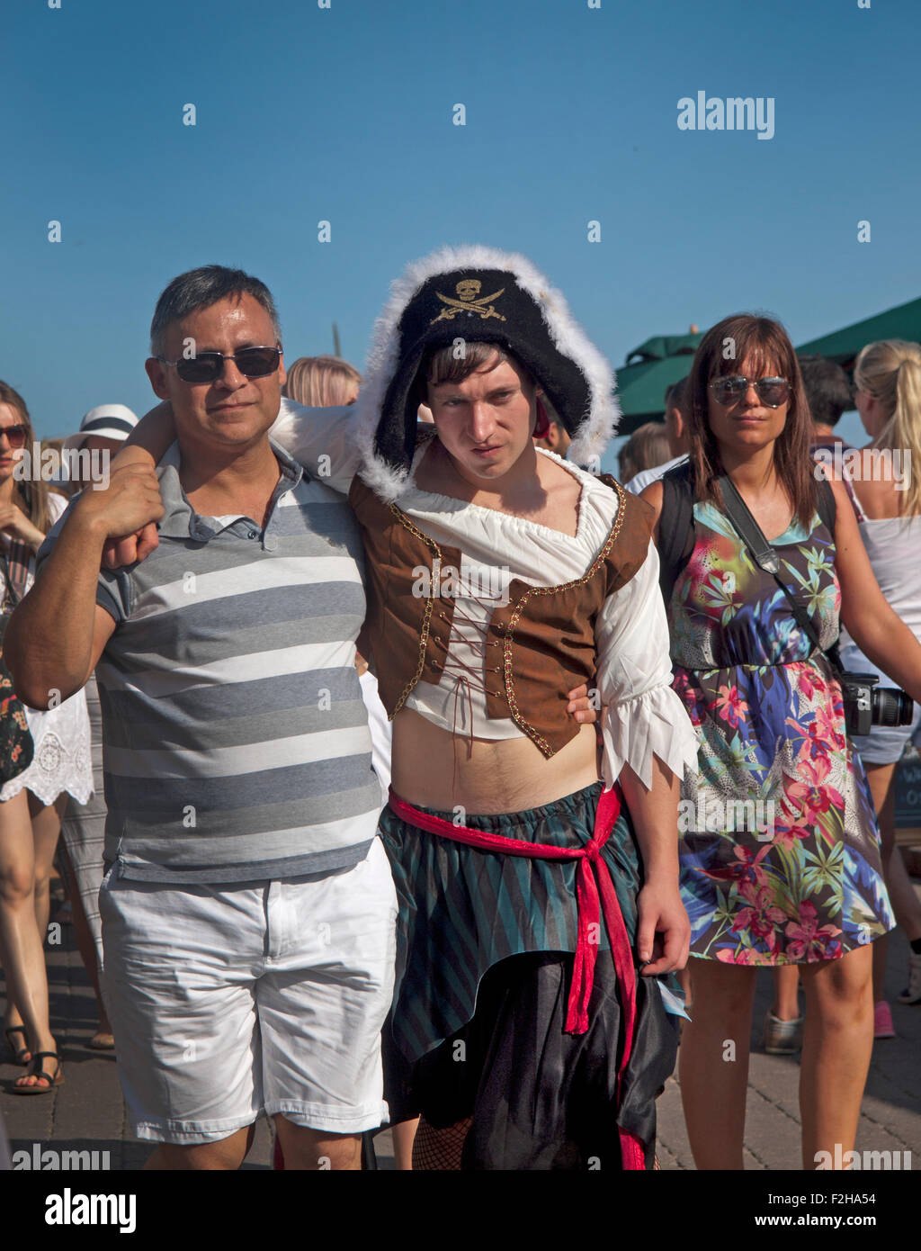 A young man on a stag do, who has drunk too much is helped along the ...