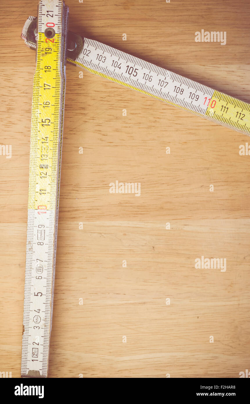 open wood yardstick on a natural wood surface - tools background with ...