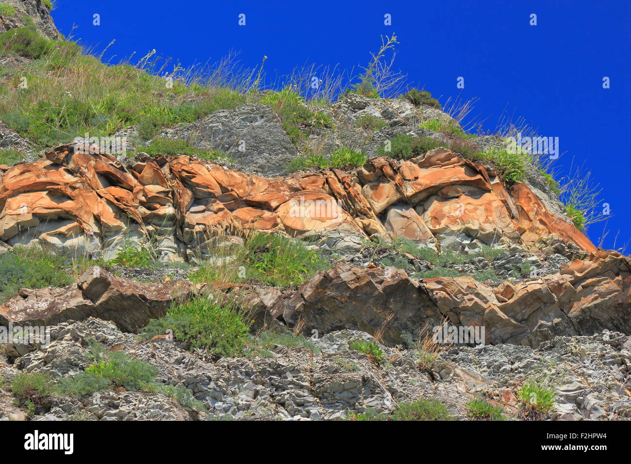 Steep slopes with sparse vegetation and visible layers of rock Stock ...