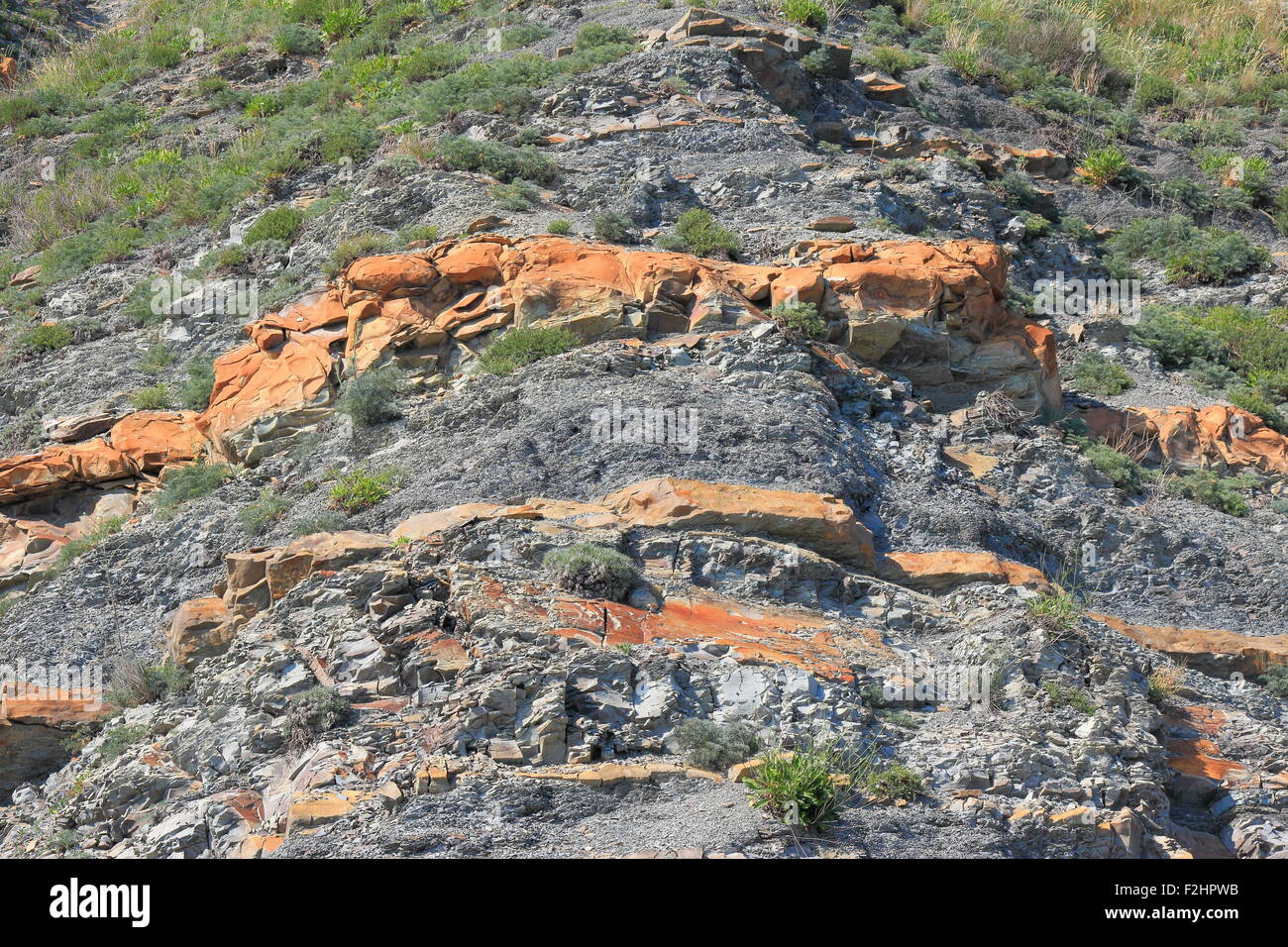 Steep slopes with sparse vegetation and visible layers of rock Stock ...