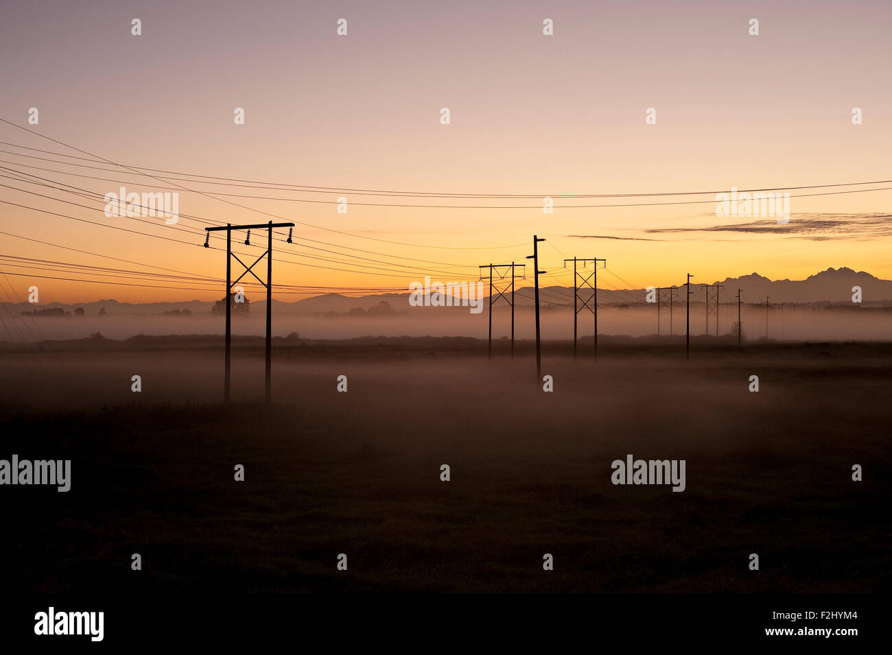 Sunrise with power lines and telephone wires stretching across valley ...