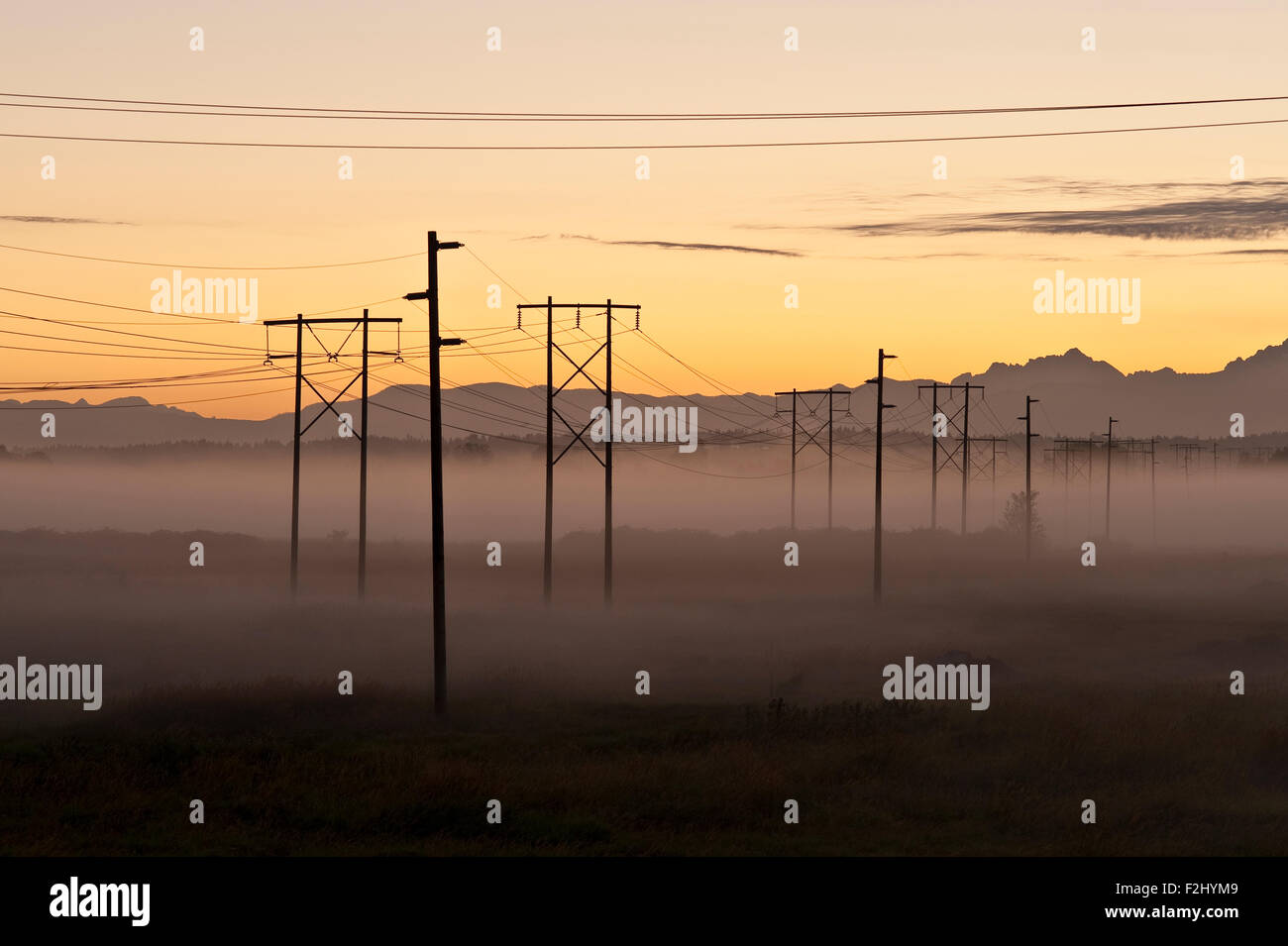 Sunrise with power lines and telephone wires stretching across valley ...