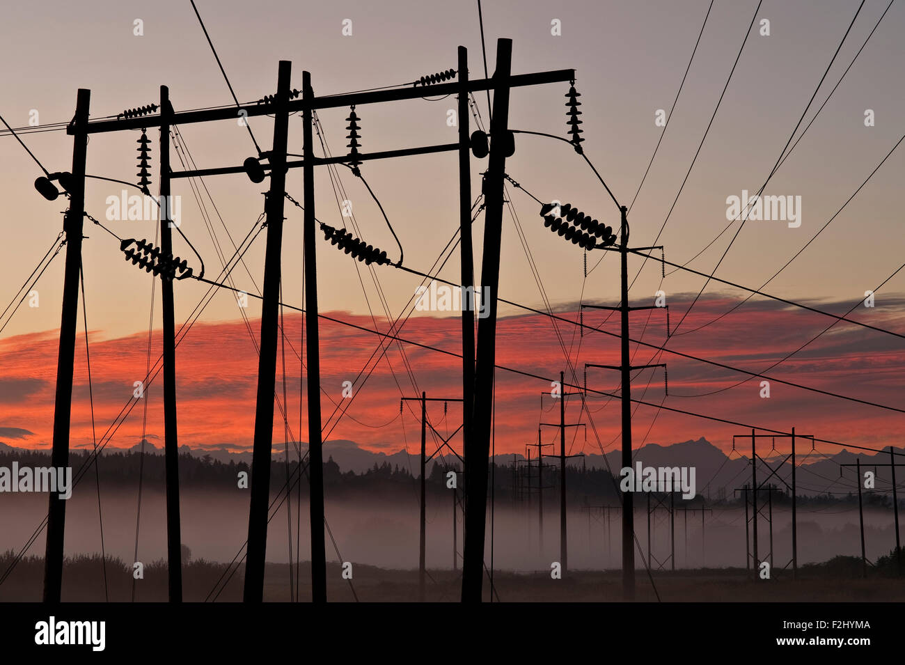 Sunrise with power lines and telephone wires stretching across valley ...
