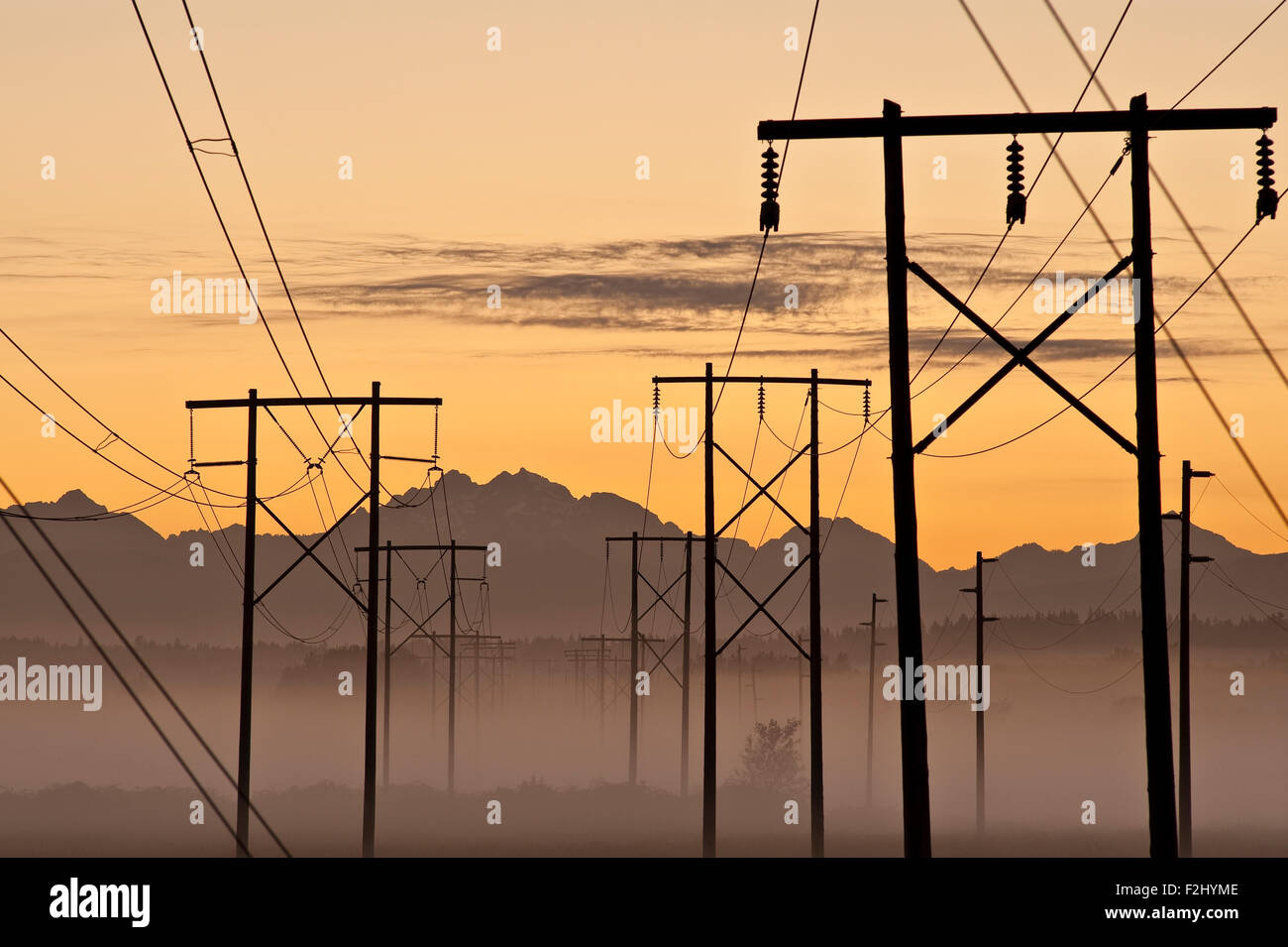 Sunrise with power lines and telephone wires stretching across valley ...