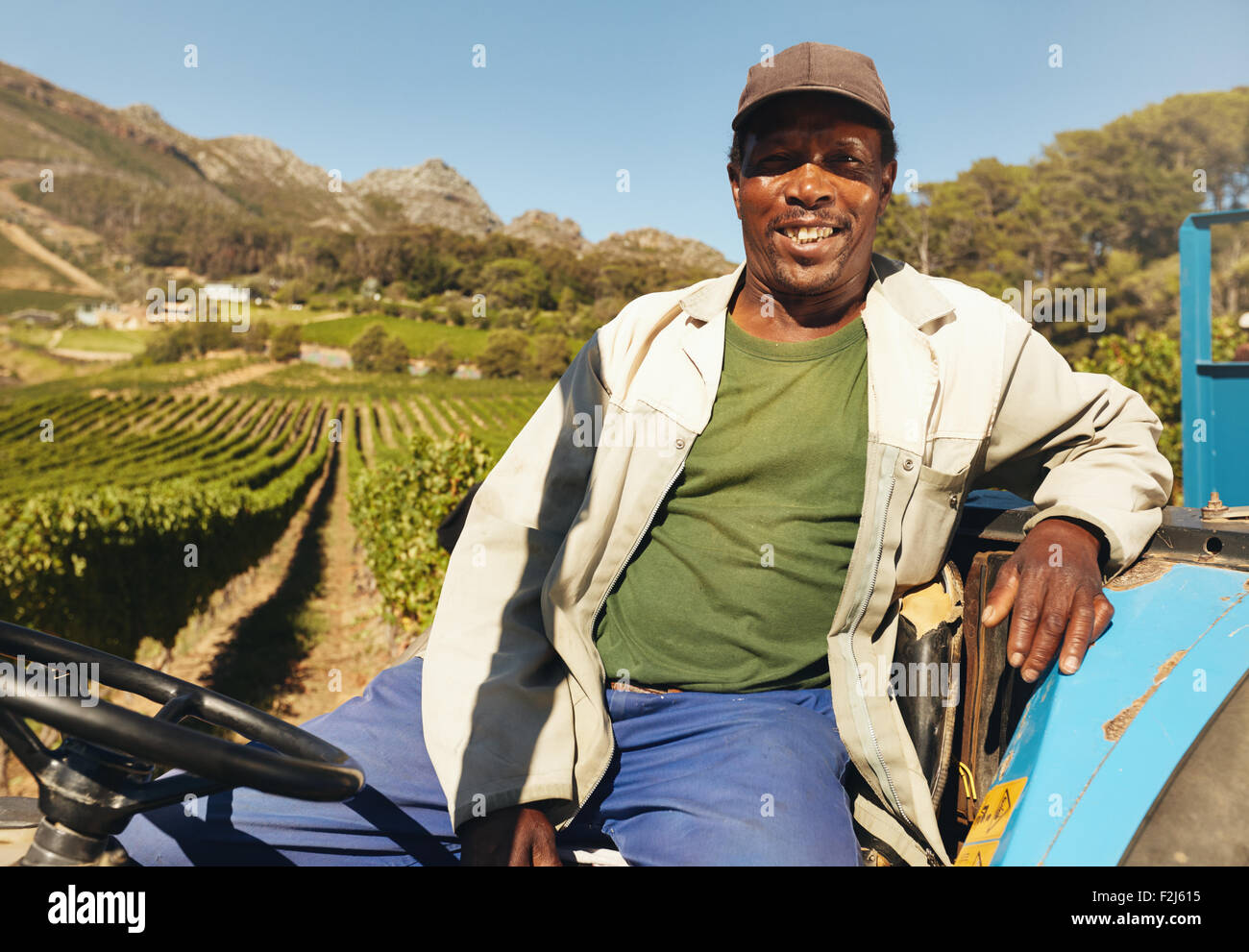 Farmer driving tractor in the fields during harvest in countryside ...