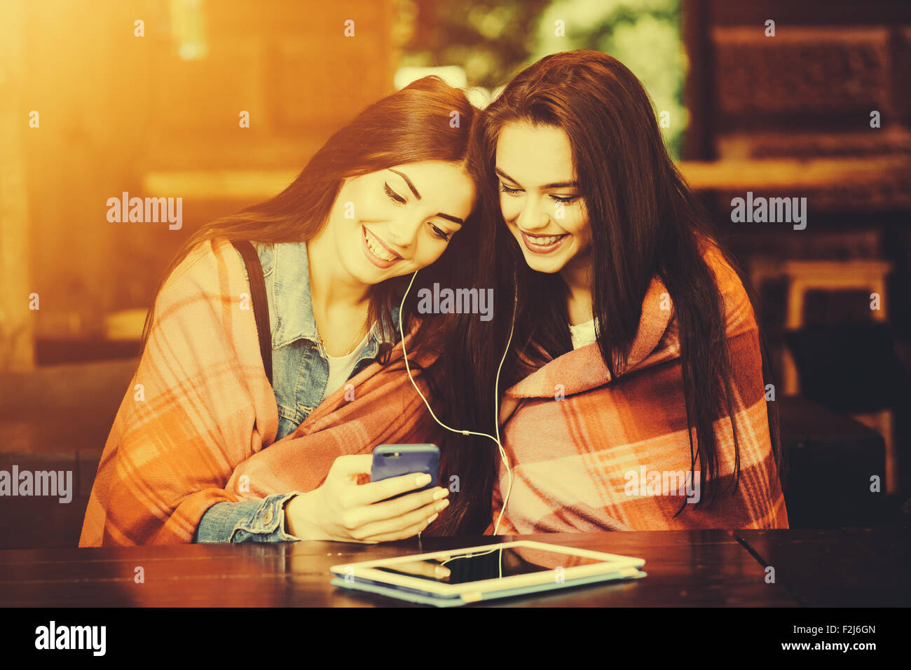 Two girl sitting listening to music Stock Photo - Alamy