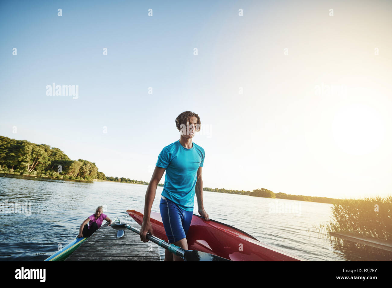 Young man carrying a kayak after getting out of the water Stock Photo ...