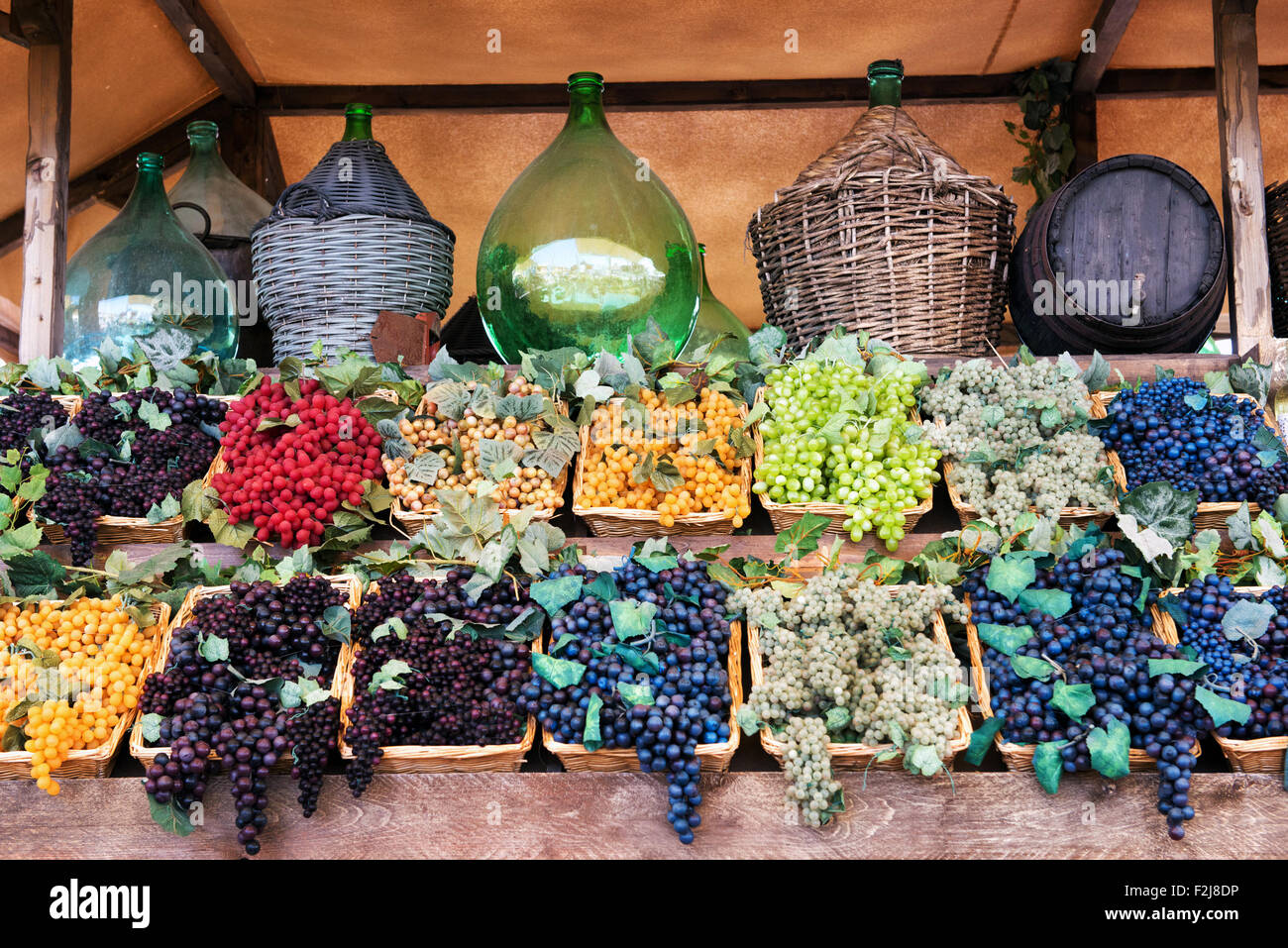 Display of assorted colored grapes in wicker trays below a shelf of old ...