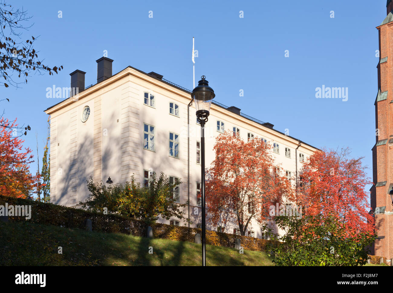 A light-colored building on a hill. Slope, lamppost and a red bricked ...