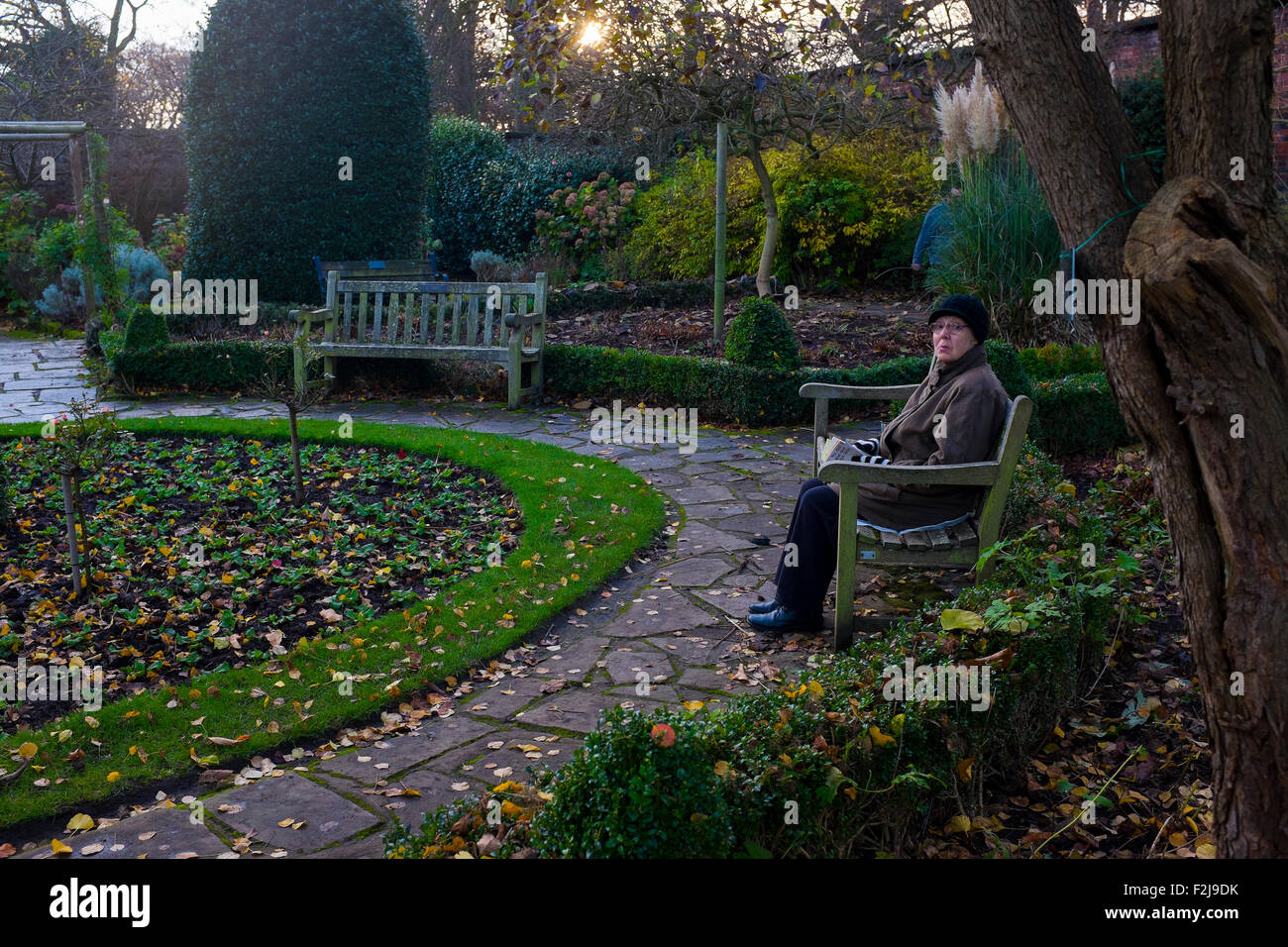 A pensioner sits on a bench in Calderstones park in Liverpool on a cool ...