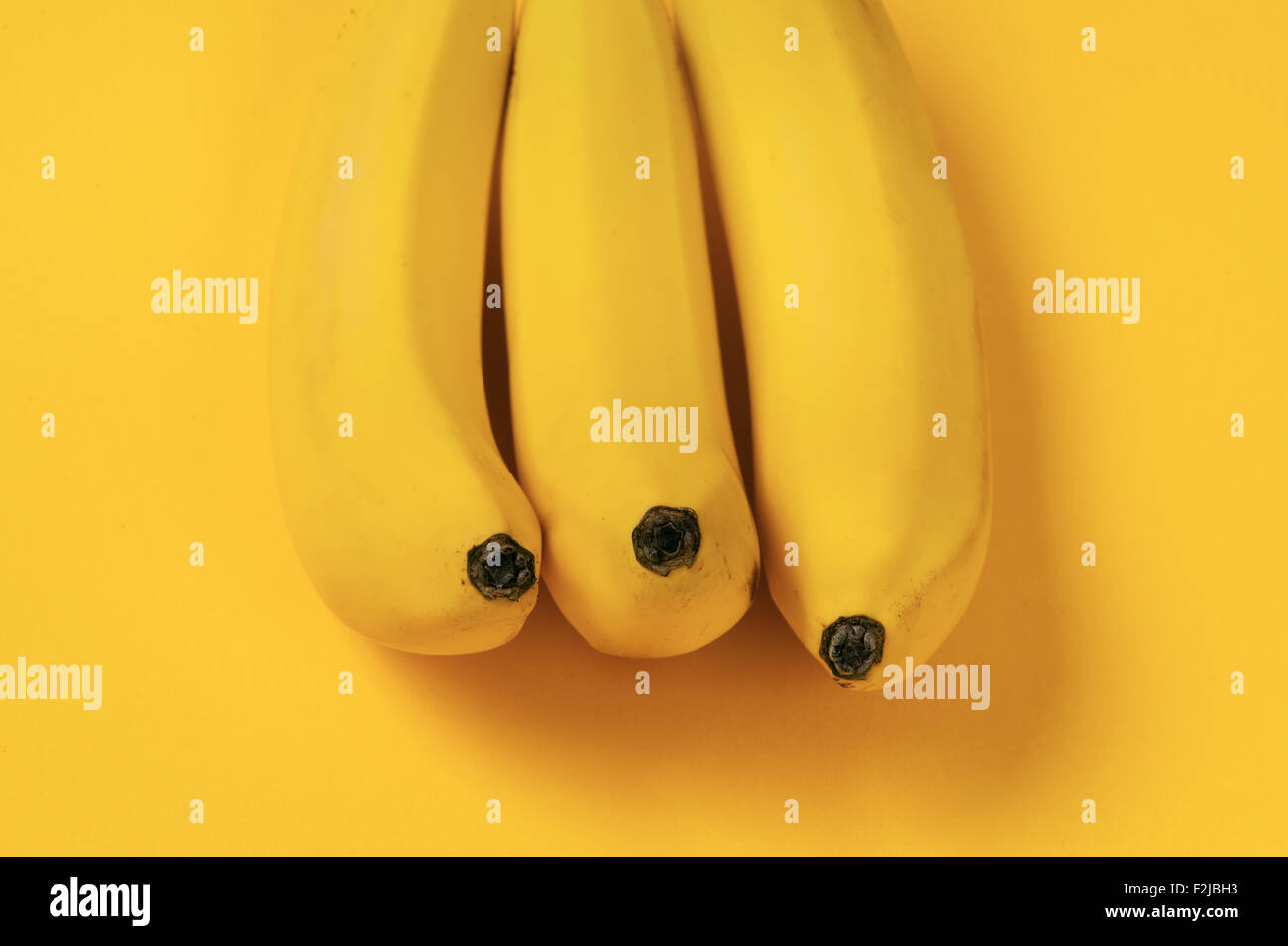 Three ripe bananas on the yellow background Stock Photo - Alamy