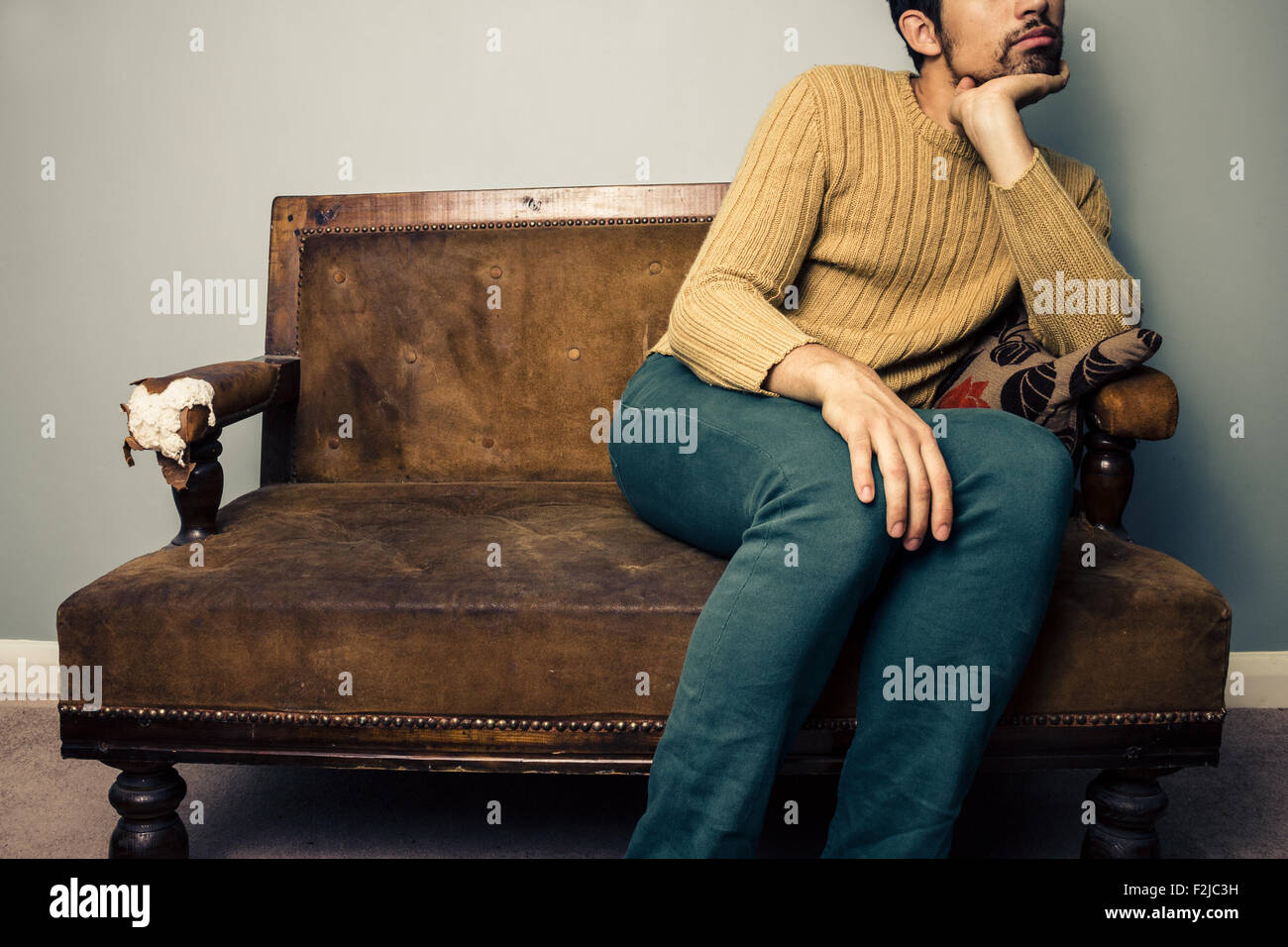 Young man sitting on sofa Stock Photo - Alamy