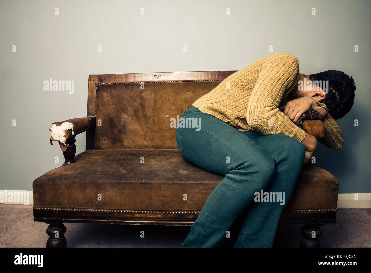 Sad young man on sofa Stock Photo - Alamy