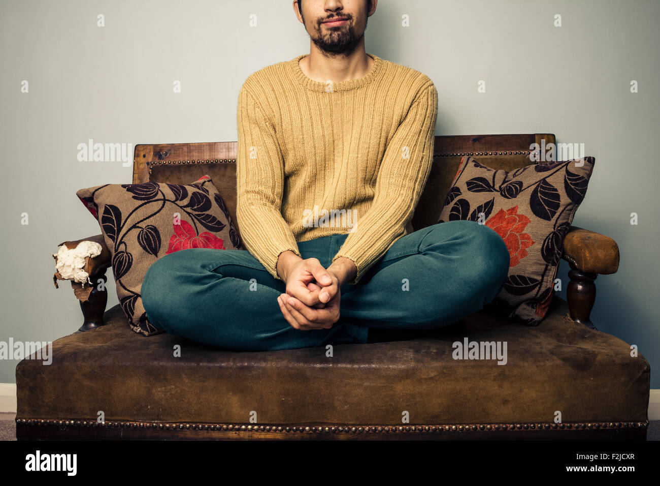 Young man sitting on sofa at home Stock Photo - Alamy