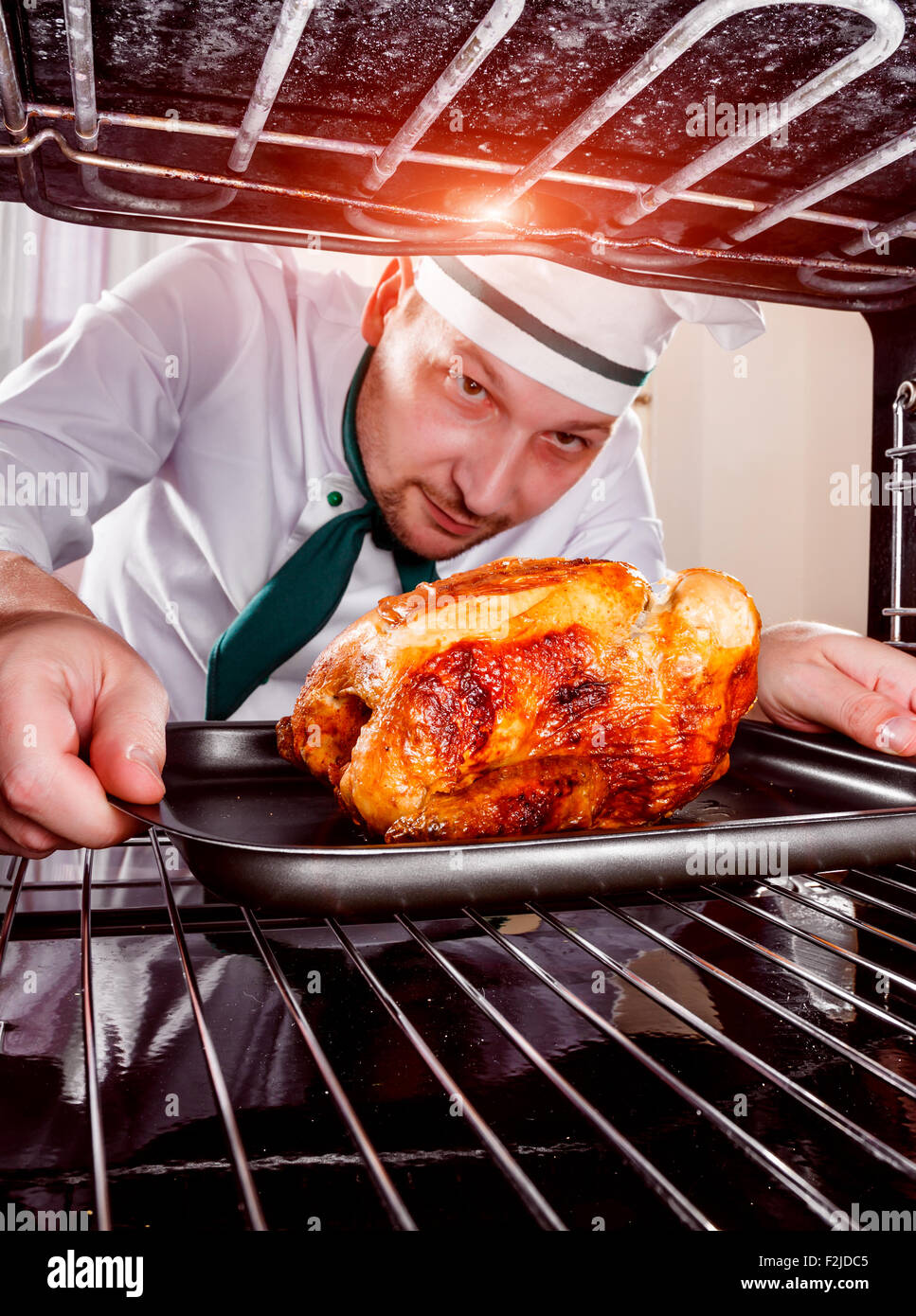 Chef prepares roast chicken (focus on chicken) in the oven, view from ...