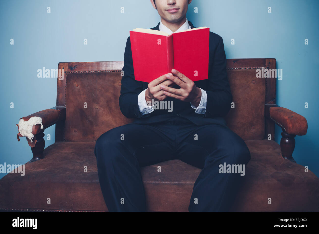 Young businessman sitting on sofa and reading Stock Photo - Alamy