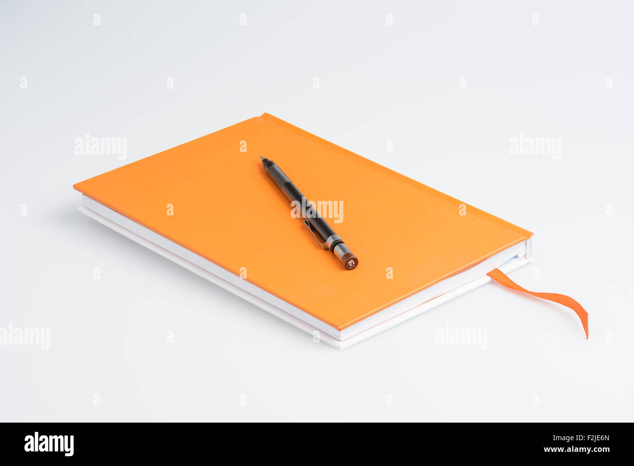 Orange note book with pen on white background Stock Photo - Alamy