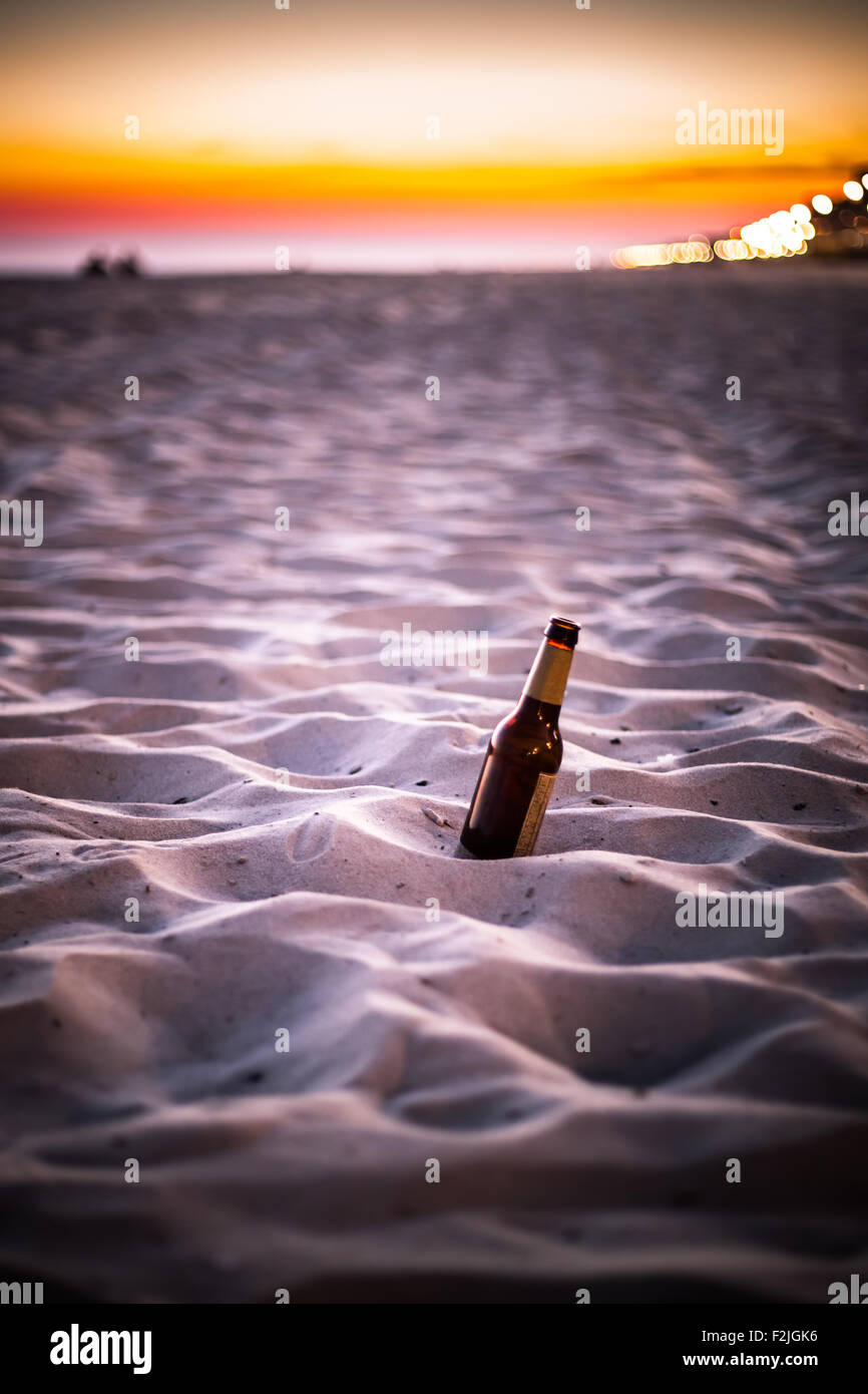 Beer bottle in sand at beach at sunset Stock Photo - Alamy