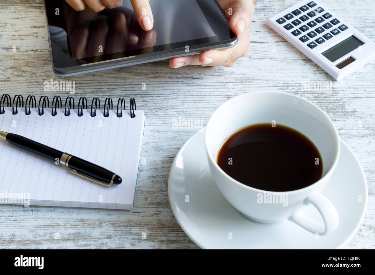 Using the tablet meanwhile drinking coffee Stock Photo - Alamy