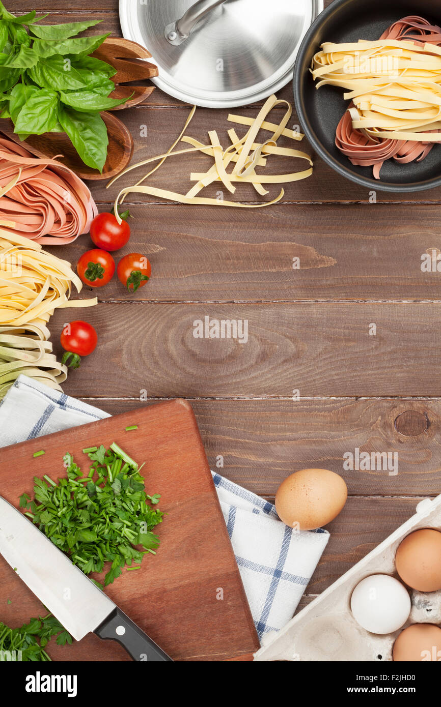 Pasta cooking ingredients and utensils on wooden table. Top view with ...