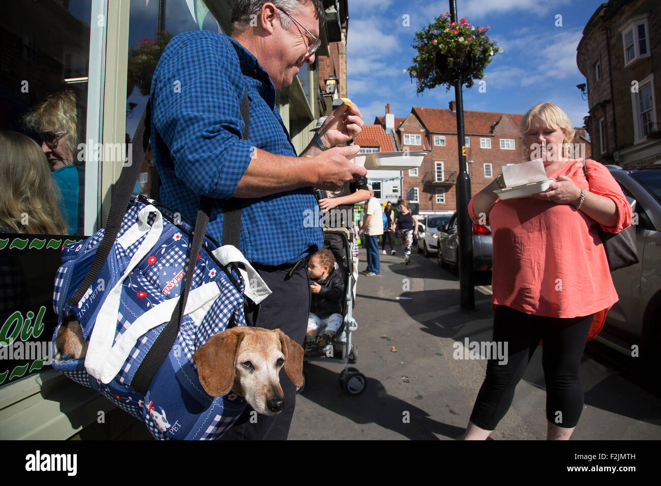 Man eating his lunch outside a fish and chip shop, with his Dachshund ...