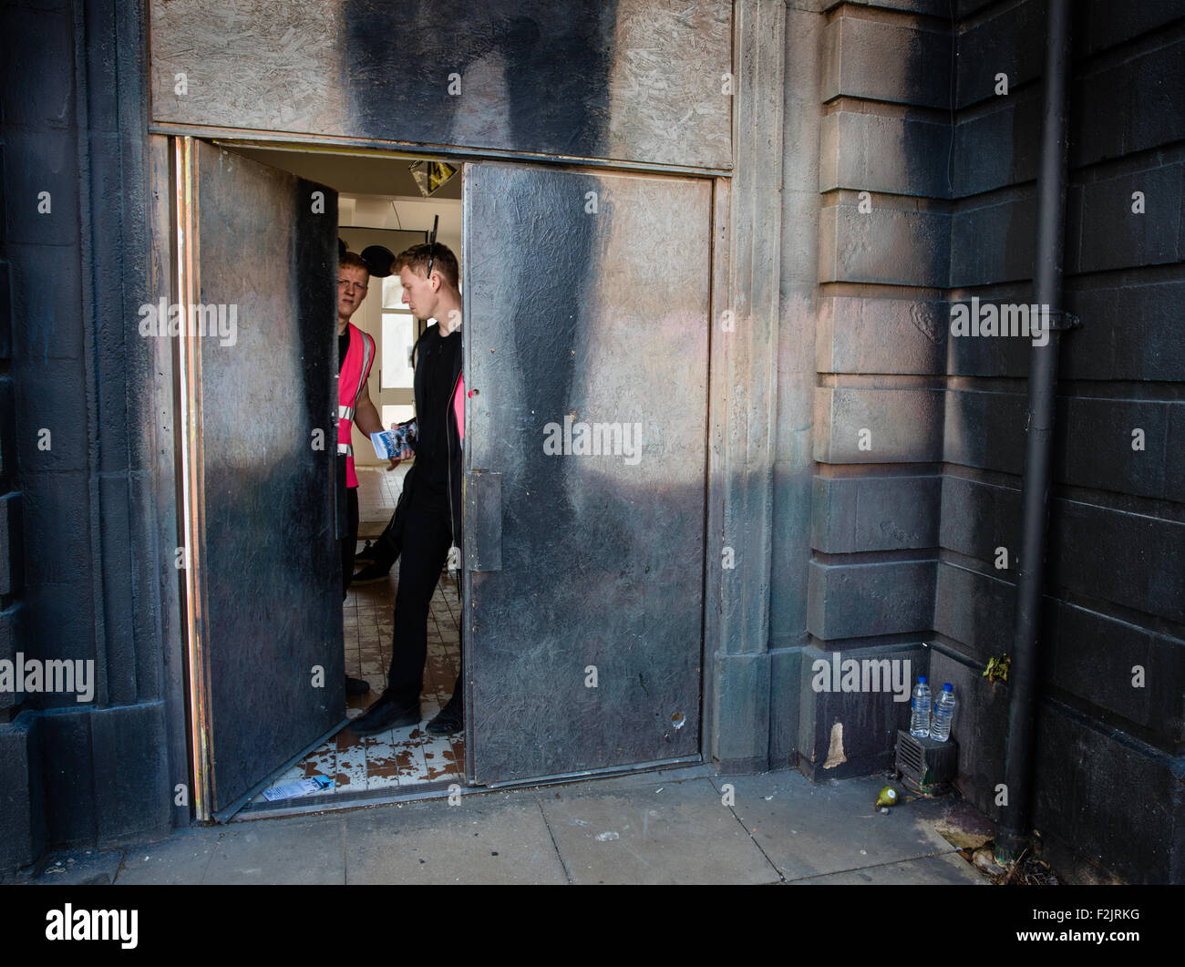 Two friendly looking staff peer out from a door ready to welcome the ...