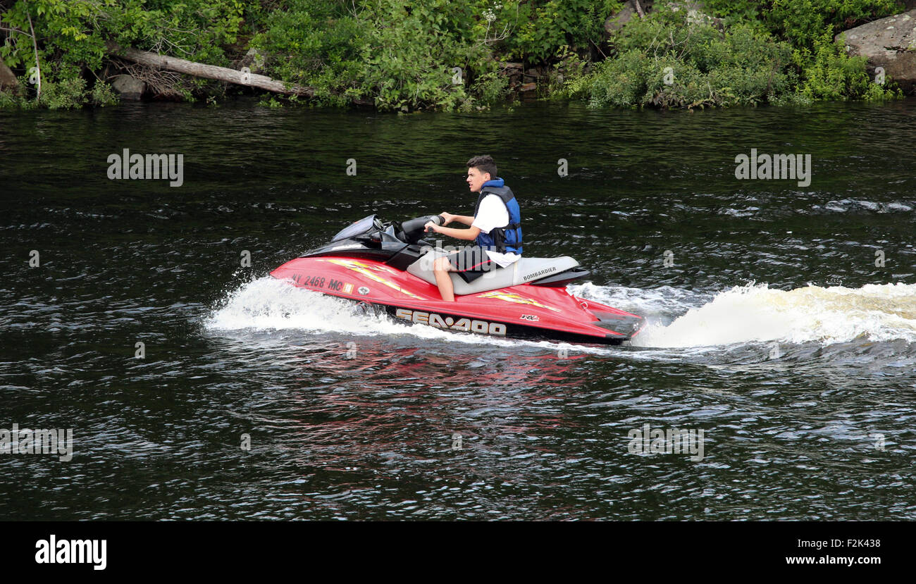 Teenage boy riding a red Sea Doo Bombardier personal watercraft. Long ...