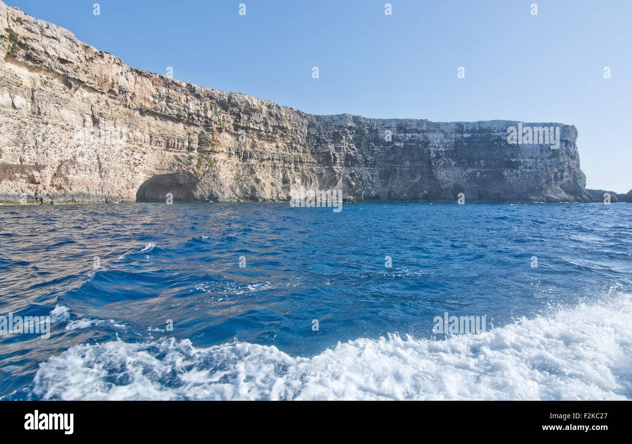 Limestone rock with caves and blue Mediterranean ocean water with white ...