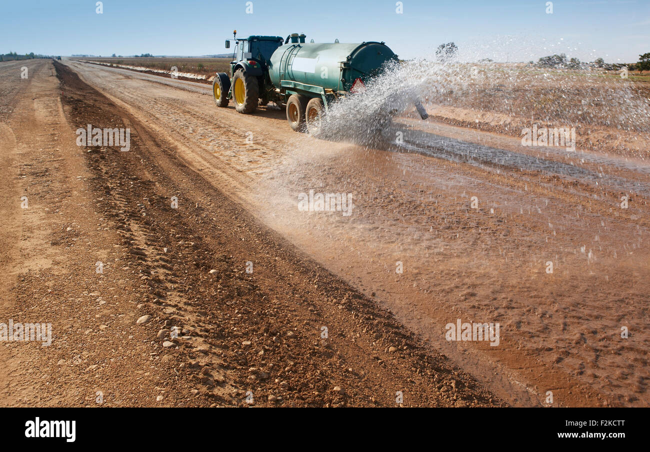 Tractor spreading water in a construction highway Stock Photo - Alamy