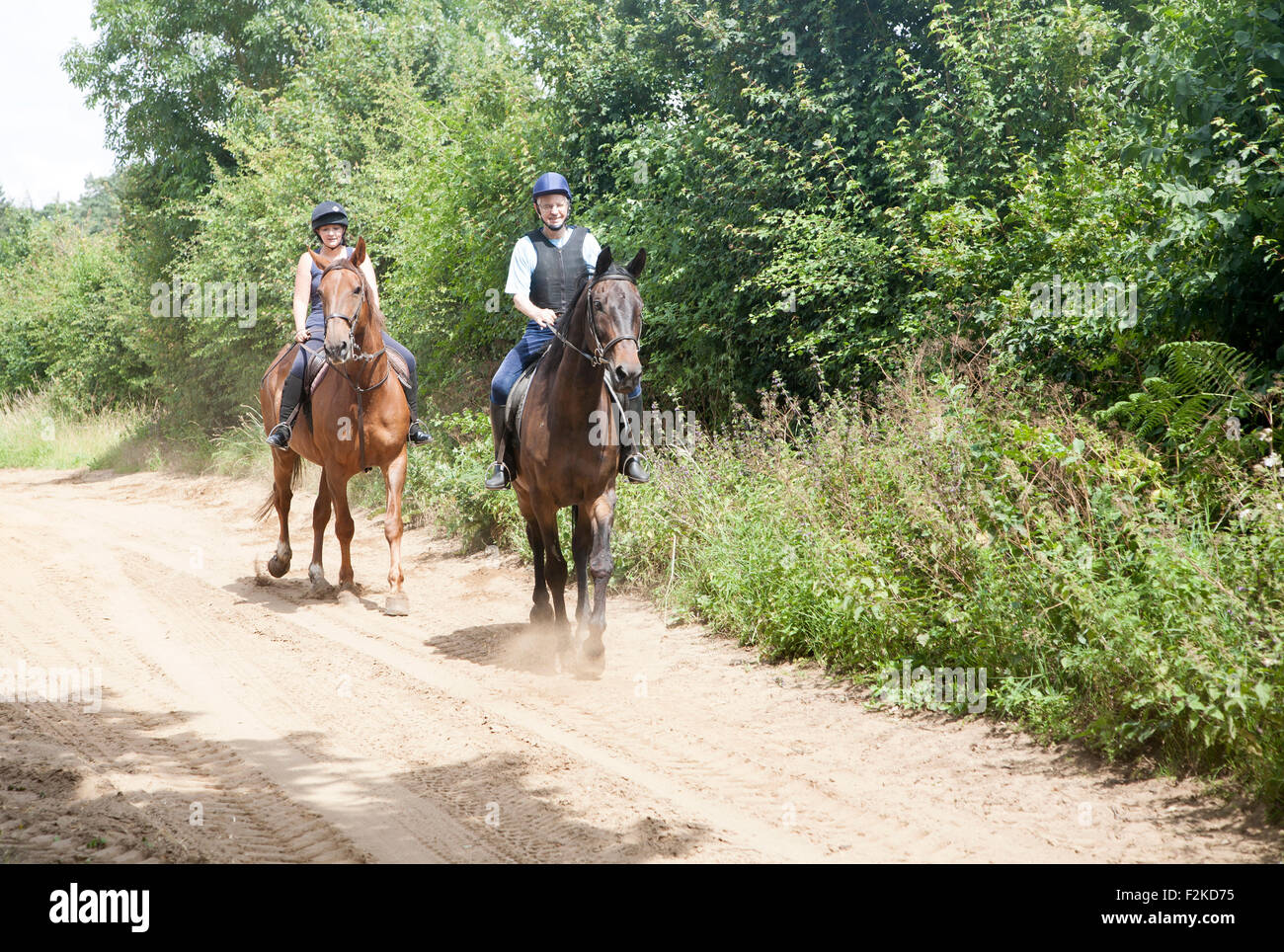 Two people riding horse on Sandlings heathland, Sutton, Suffolk ...