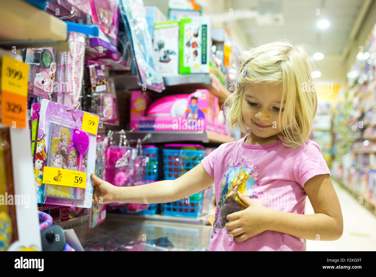 Little child blond girl choosing and shopping a toy in the toy store ...