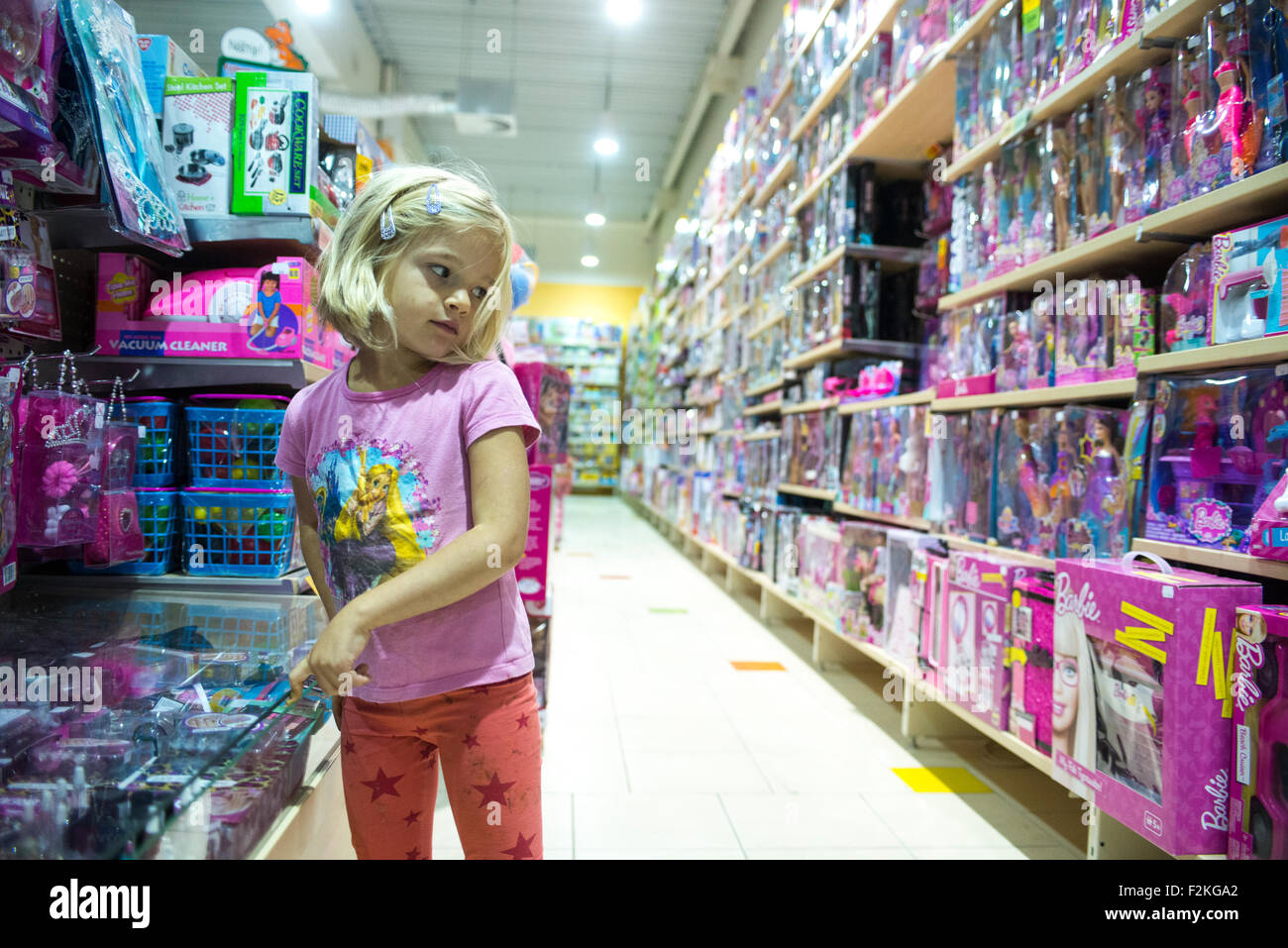 Little child blond girl choosing and shopping a toy in the toy store ...